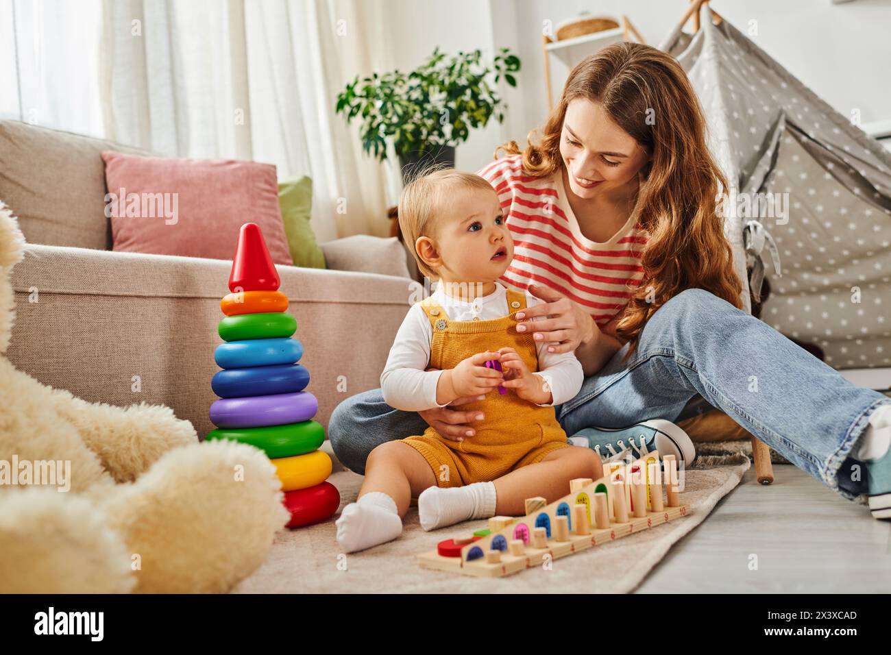 A young mother joyfully engages with her toddler daughter, playfully ...