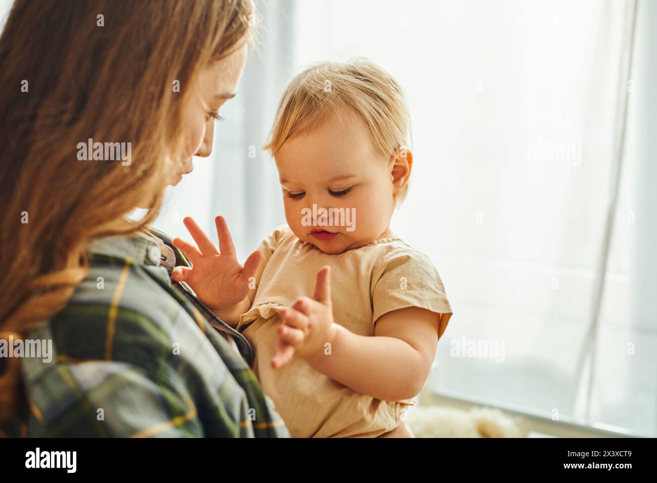 A young mother tenderly holding her toddler daughter in her lap ...