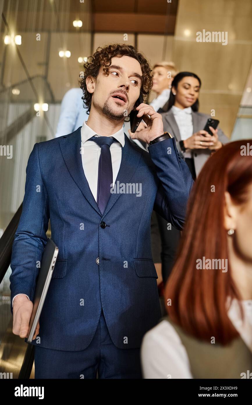 A man in a sharp suit engages in a phone call next to his colleagues ...