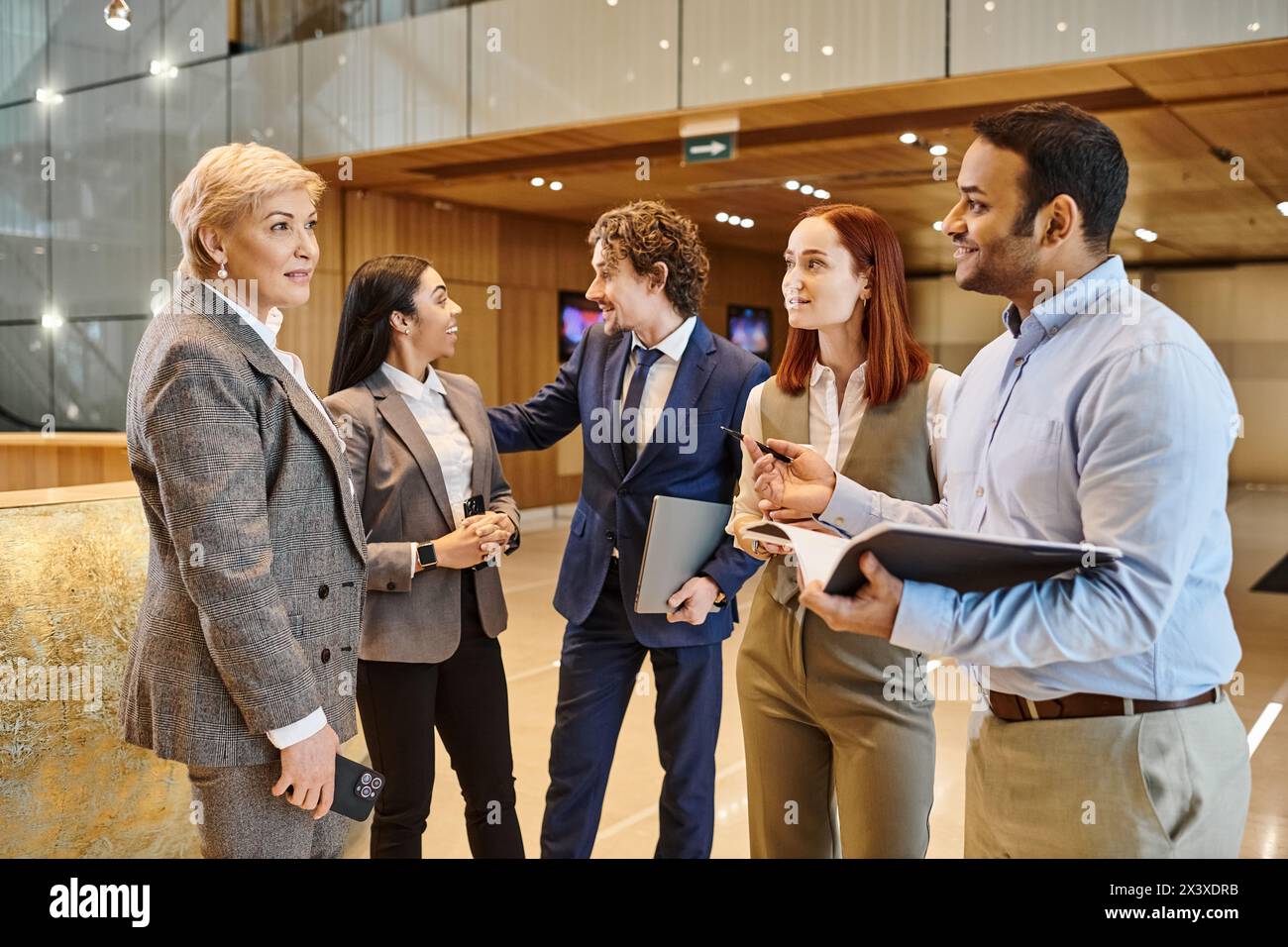 Diverse business team standing together in a lobby, discussing and ...