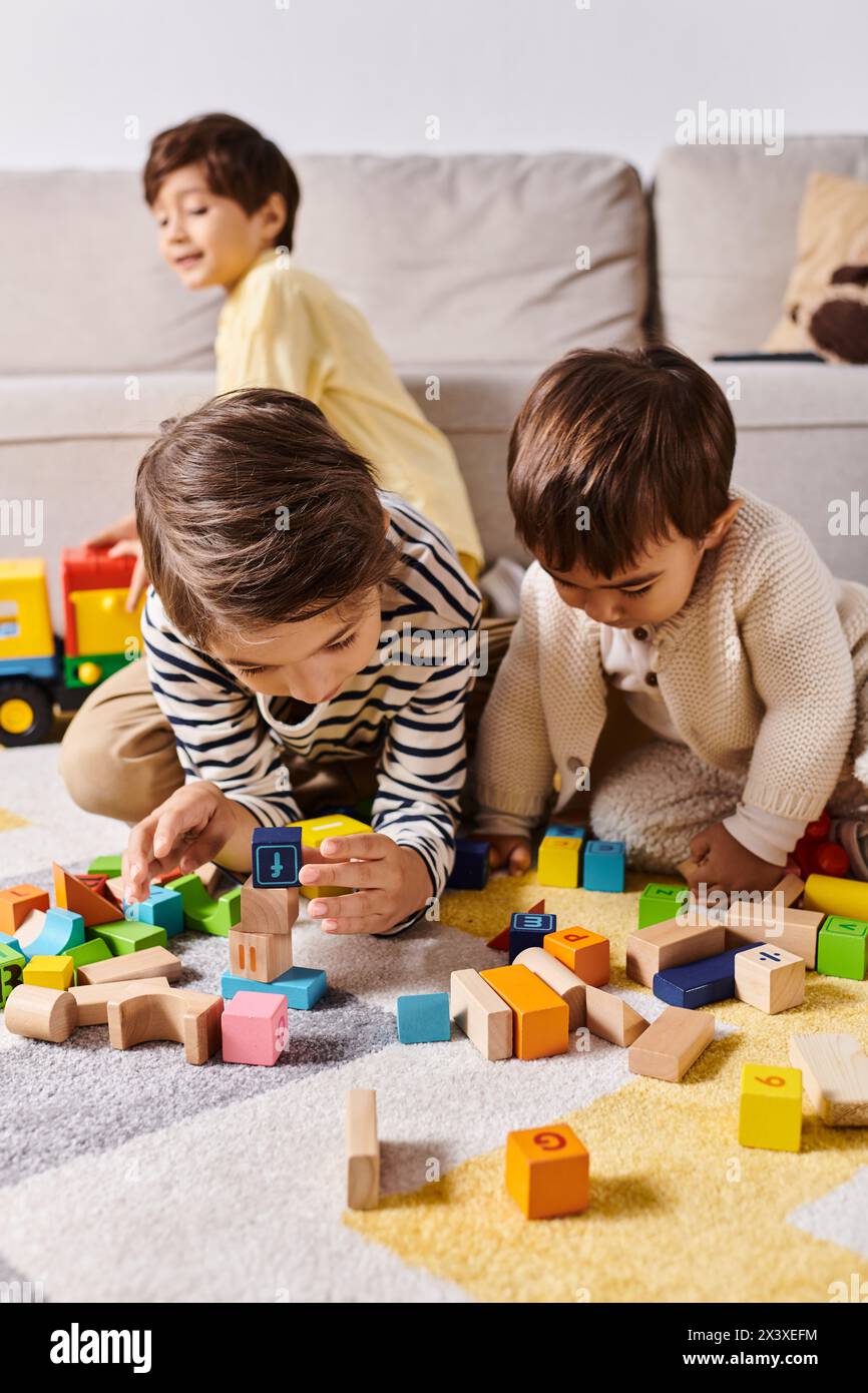 Two children, happily play and build with wooden blocks on the floor of ...