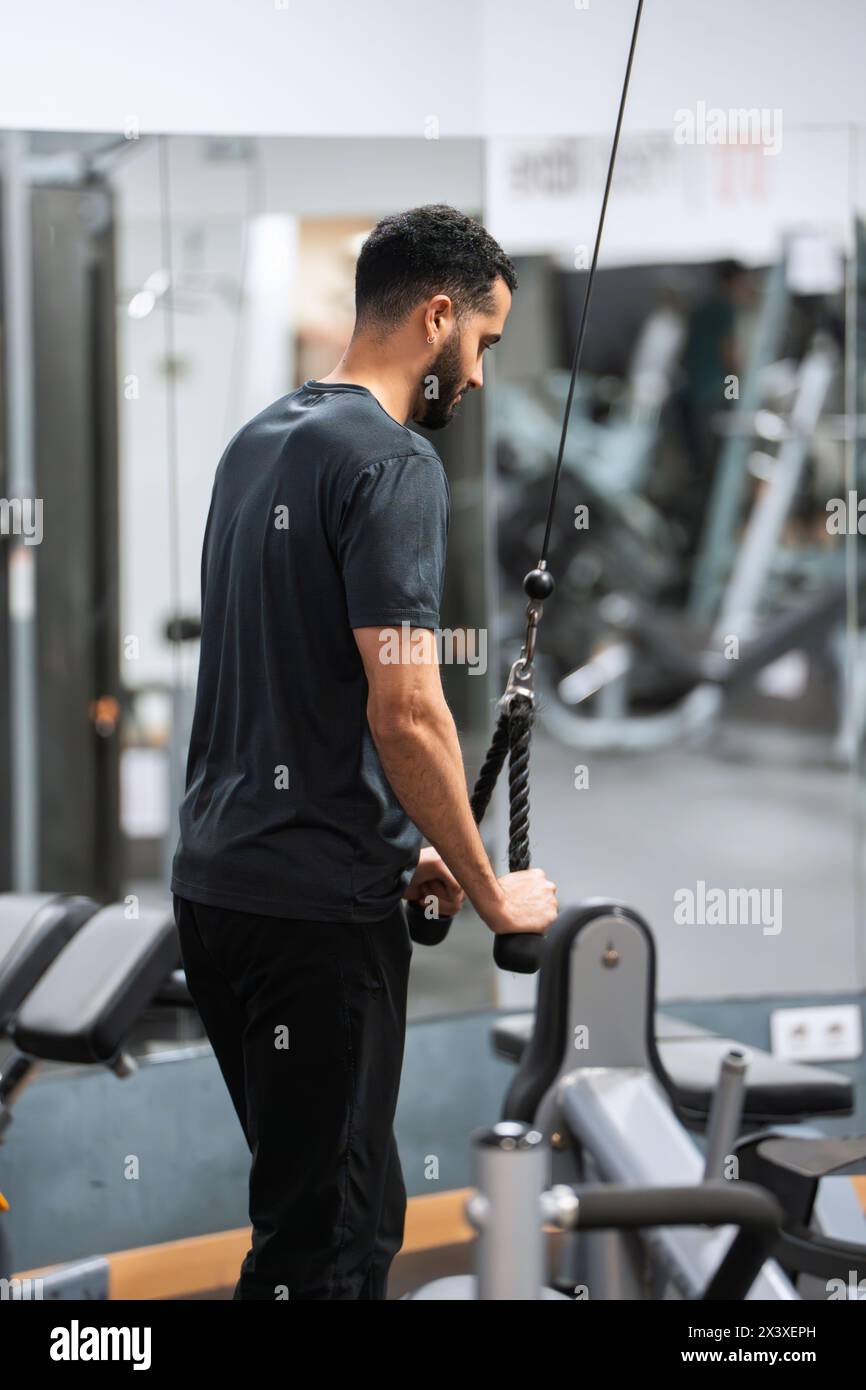 Focused gym-goer performing tricep pushdowns with a rope attachment at ...