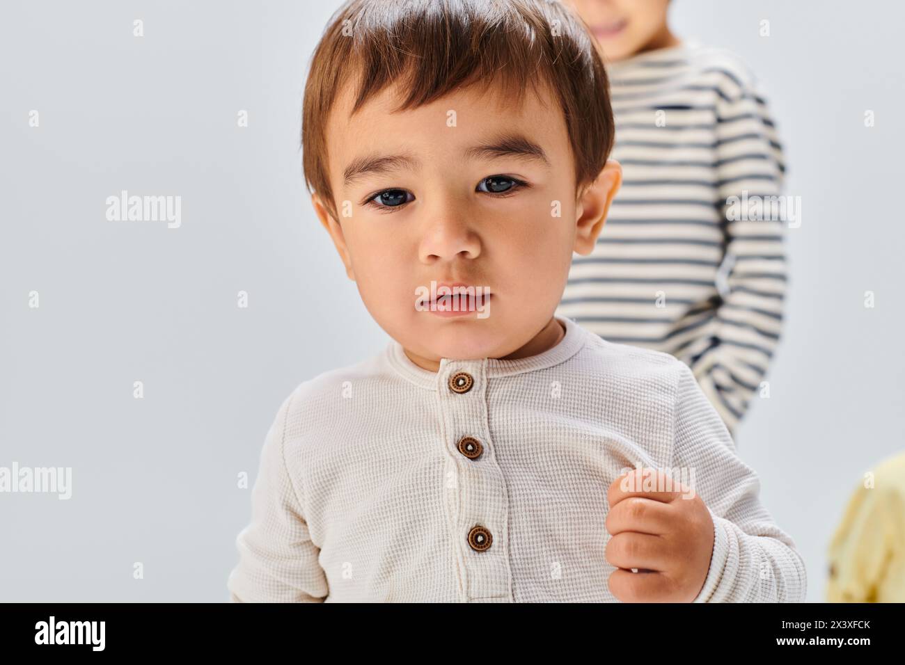 A young boy stands next to brother in a studio, forming a heartwarming ...