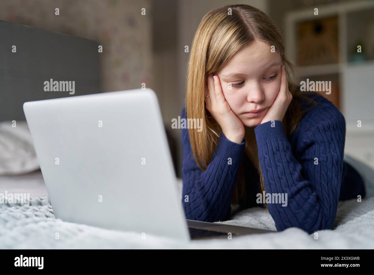 Unhappy Teenage Girl With Laptop Lying On Bed At Home Anxious About ...