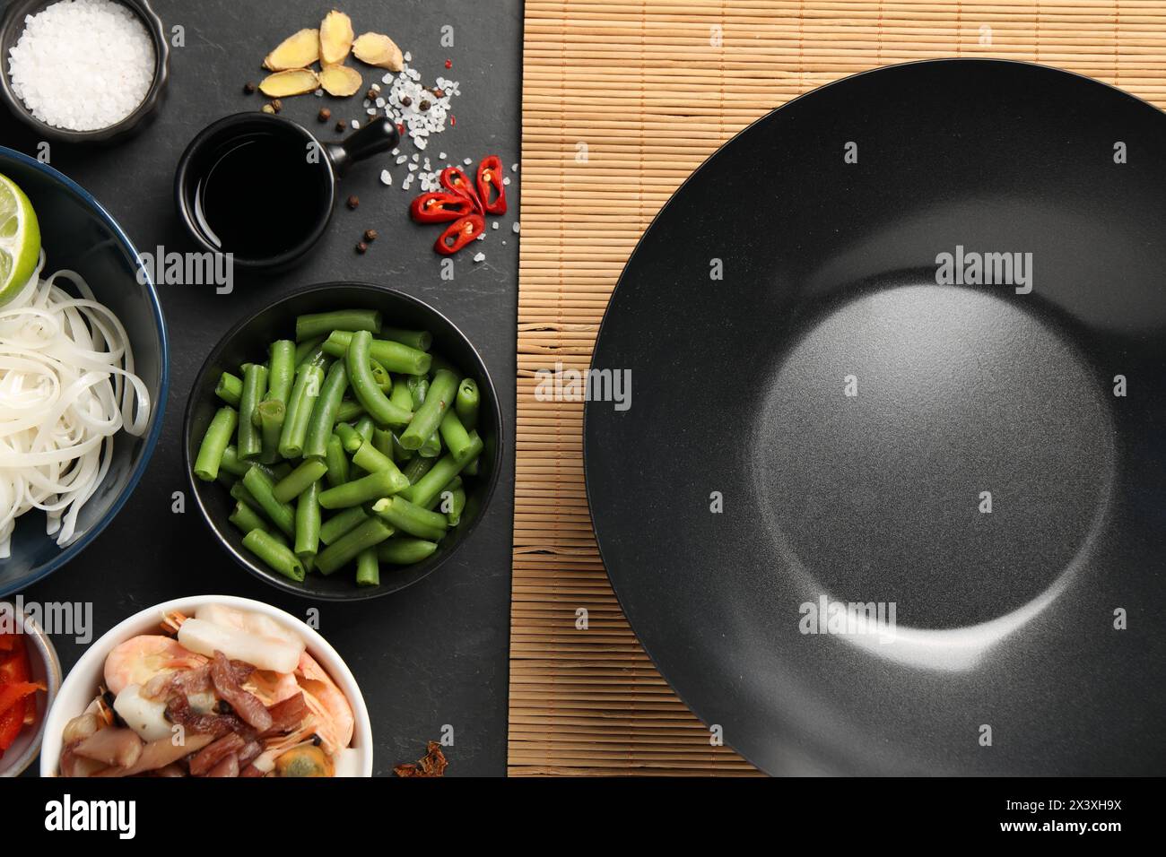 Flat lay composition with black wok, spices and products on dark ...