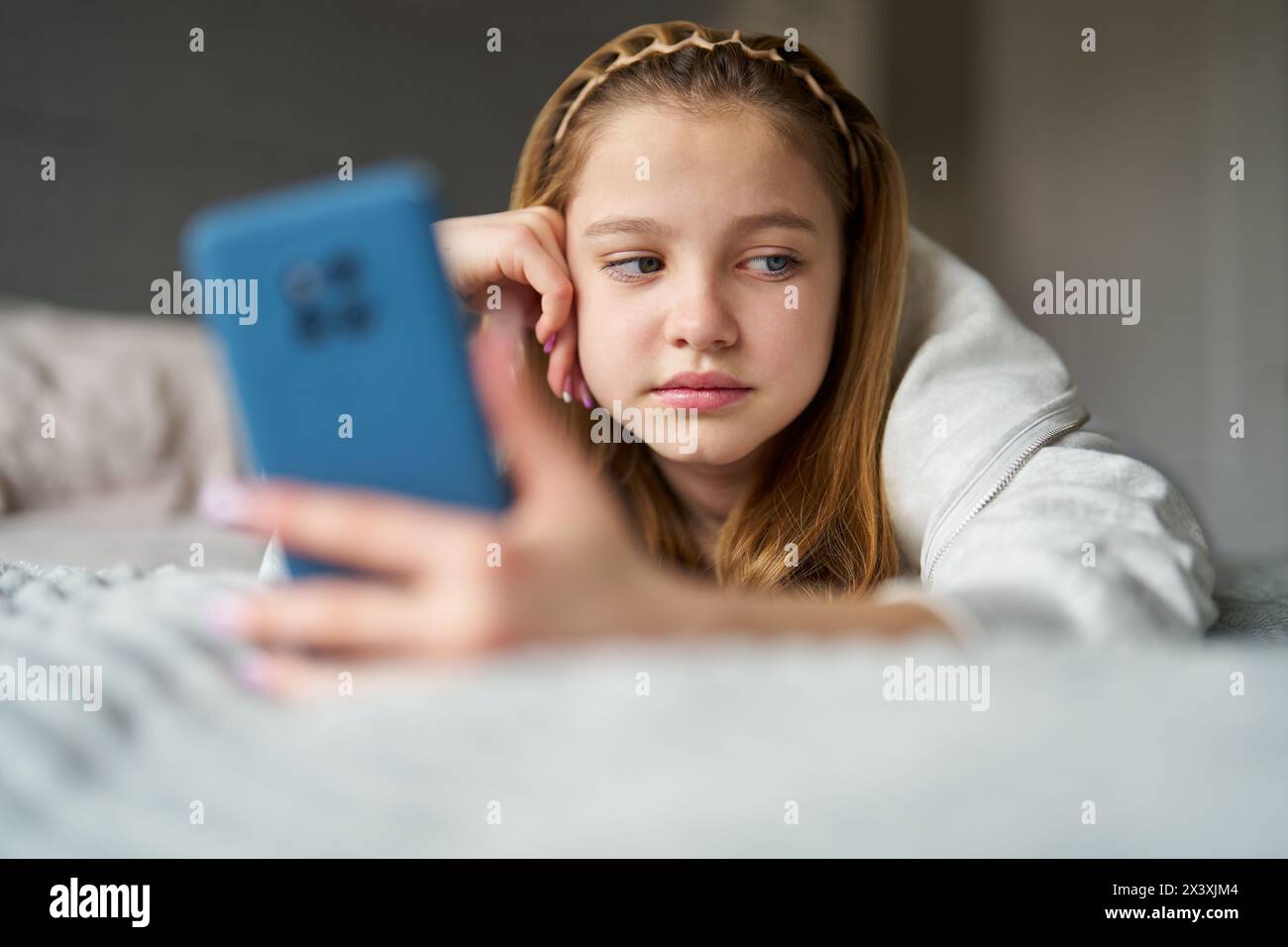 Unhappy Teenage Girl With Mobile Phone Lying On Bed At Home Anxious ...