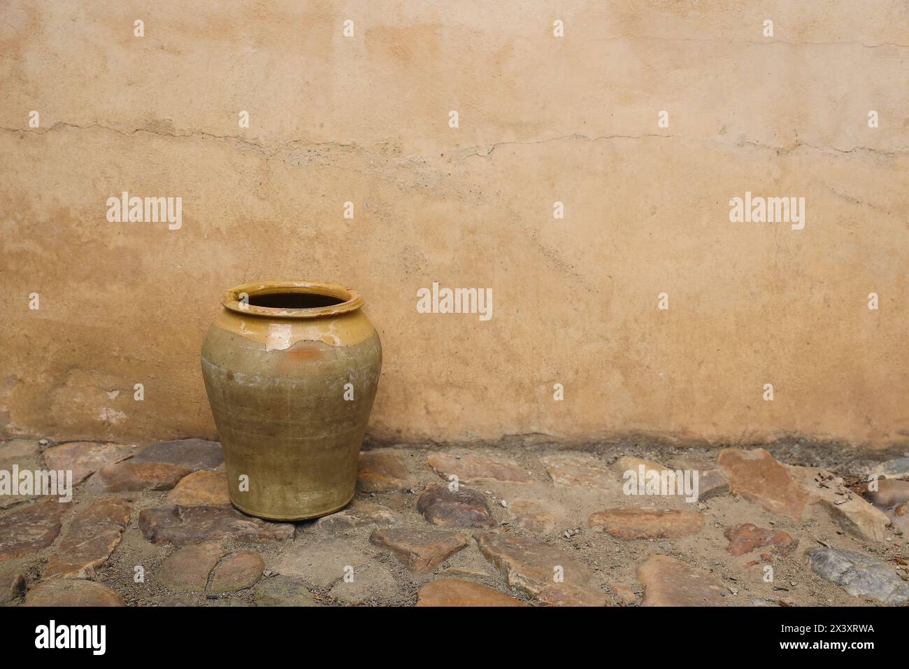 Rustic yellow clay vase on cobble stone floor, pavement against shabby ...