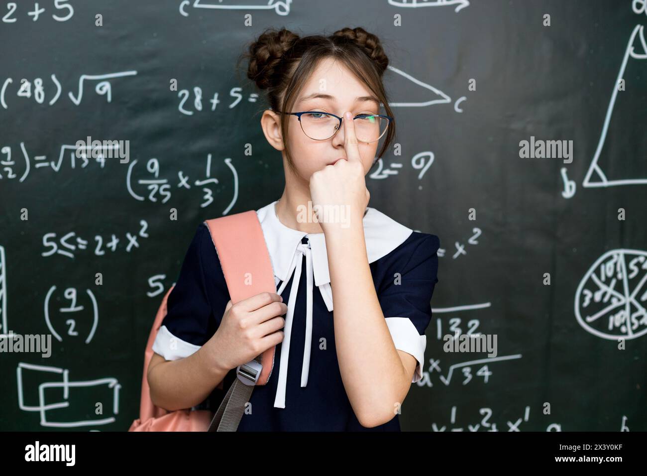 beautiful schoolgirl adjusts her glasses on her nose while standing at ...
