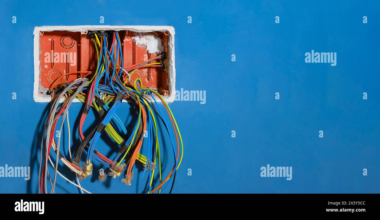 Colored electrical cables coming out of an open junction box, during ...