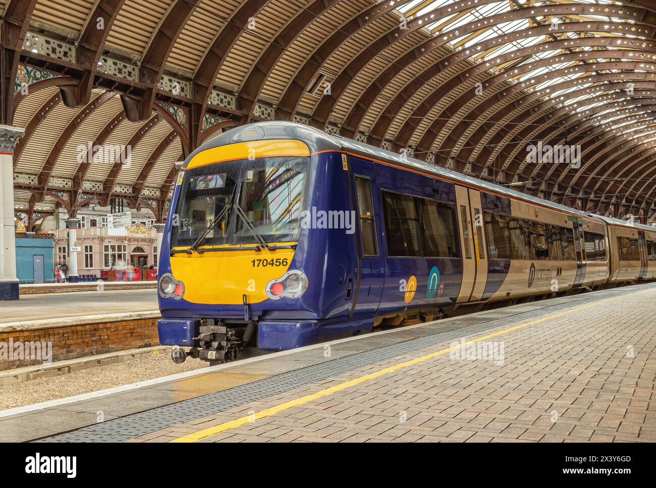 A train stands at a railway station platform covered by a historic ...
