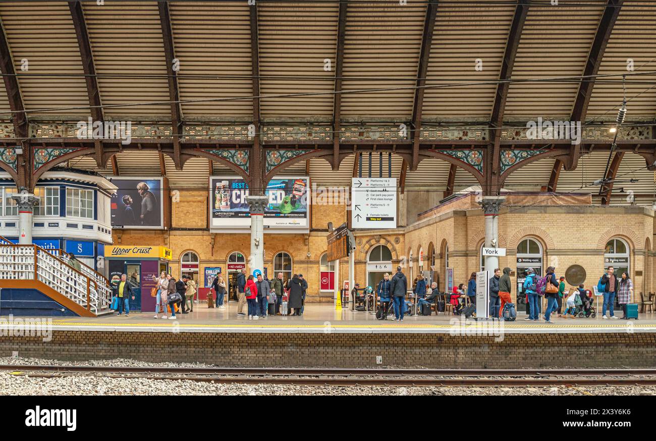 A railway station concourse is crowded with passengers waiting for ...