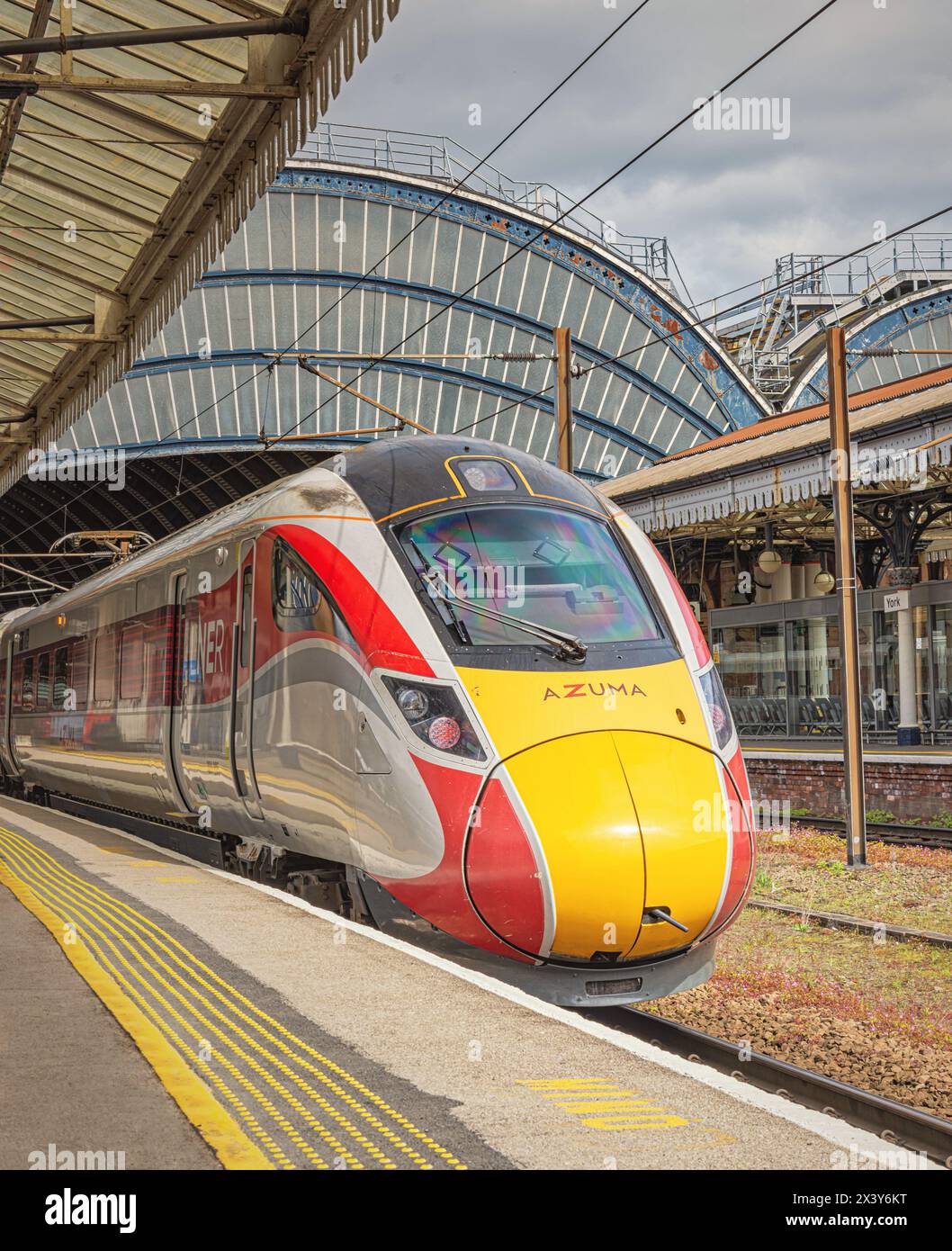 A train rests by a railway station historic platform. Metal arches are ...