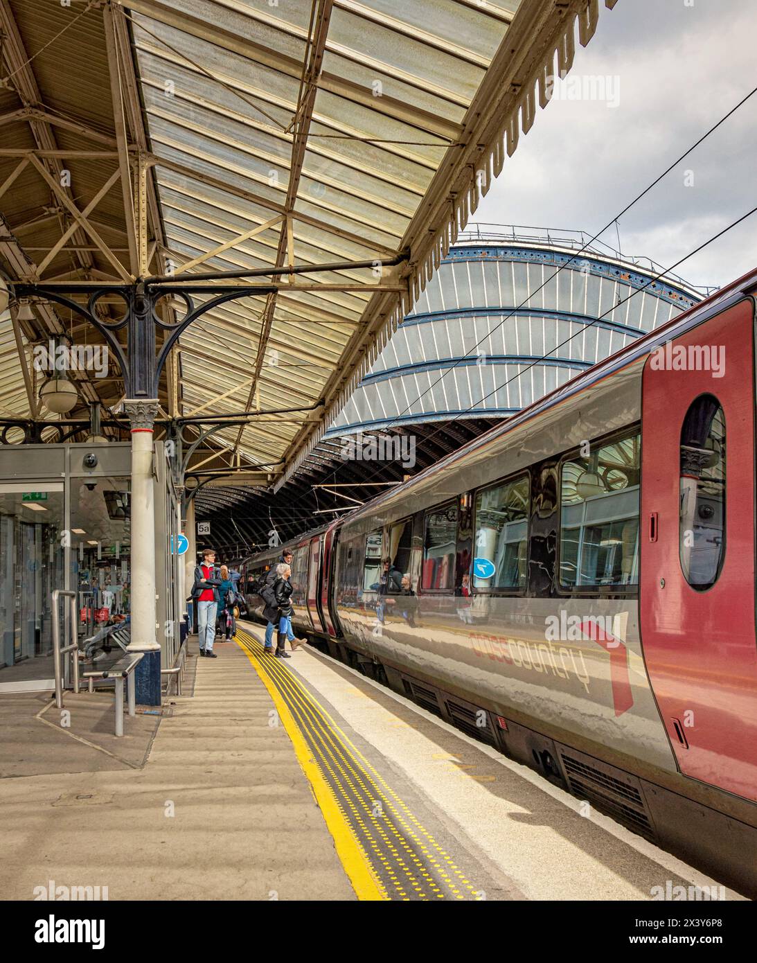 A train stands by a historic 19th Century canopy with columns. Metal ...