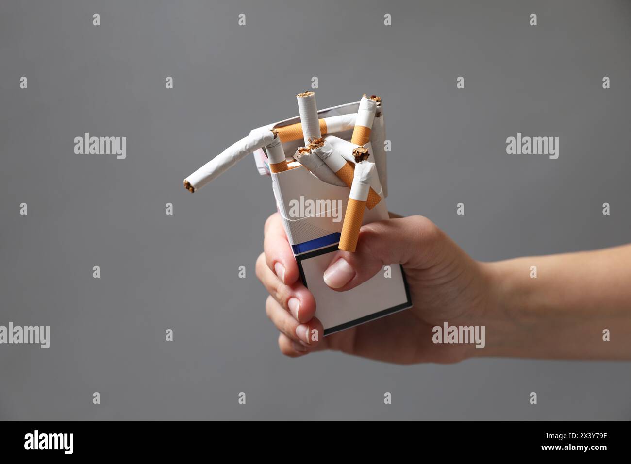 Stop smoking. Woman holding pack with broken cigarettes on grey ...