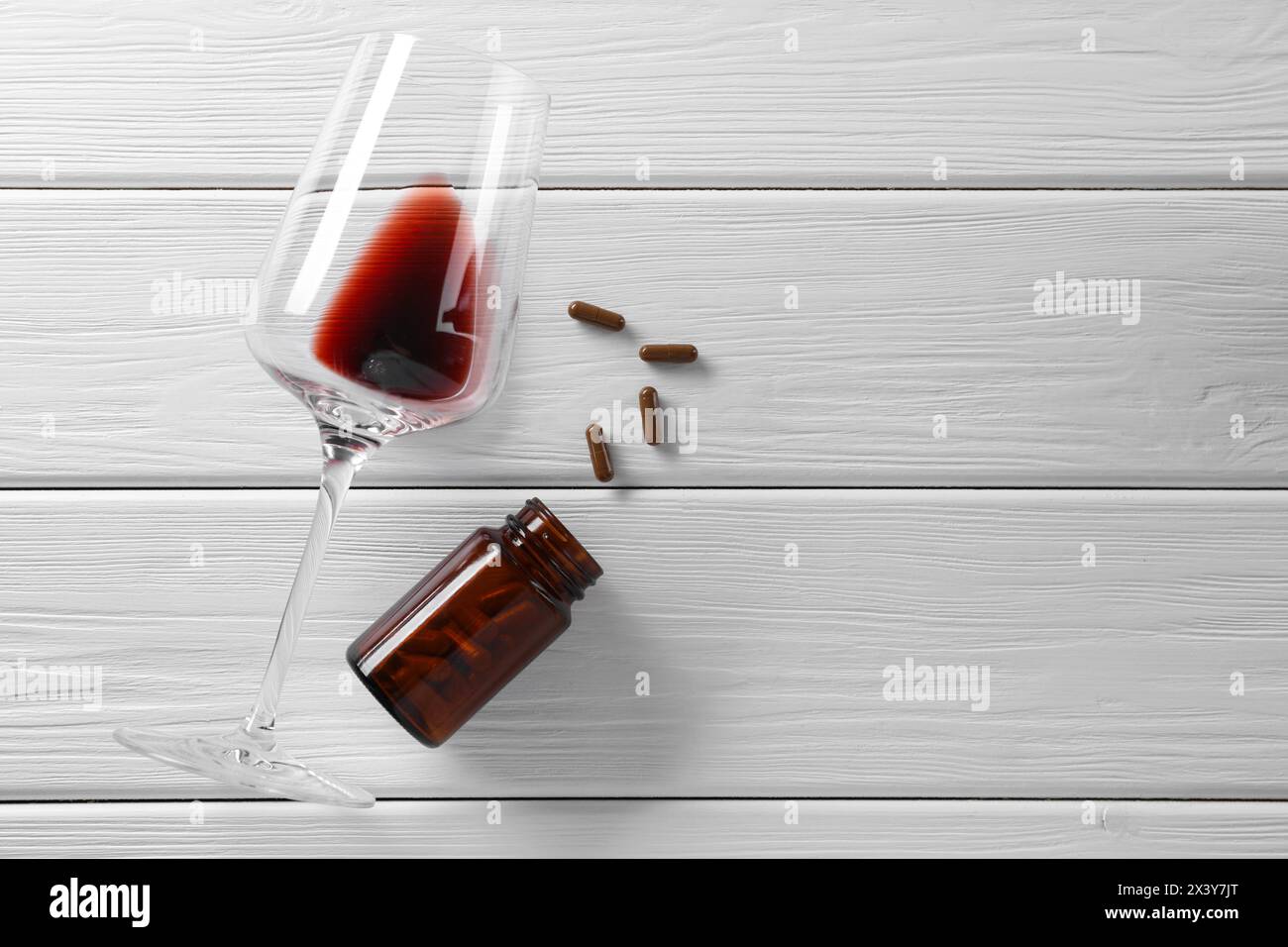 Alcohol and drug addiction. Glass with red wine, bottle and pills on ...