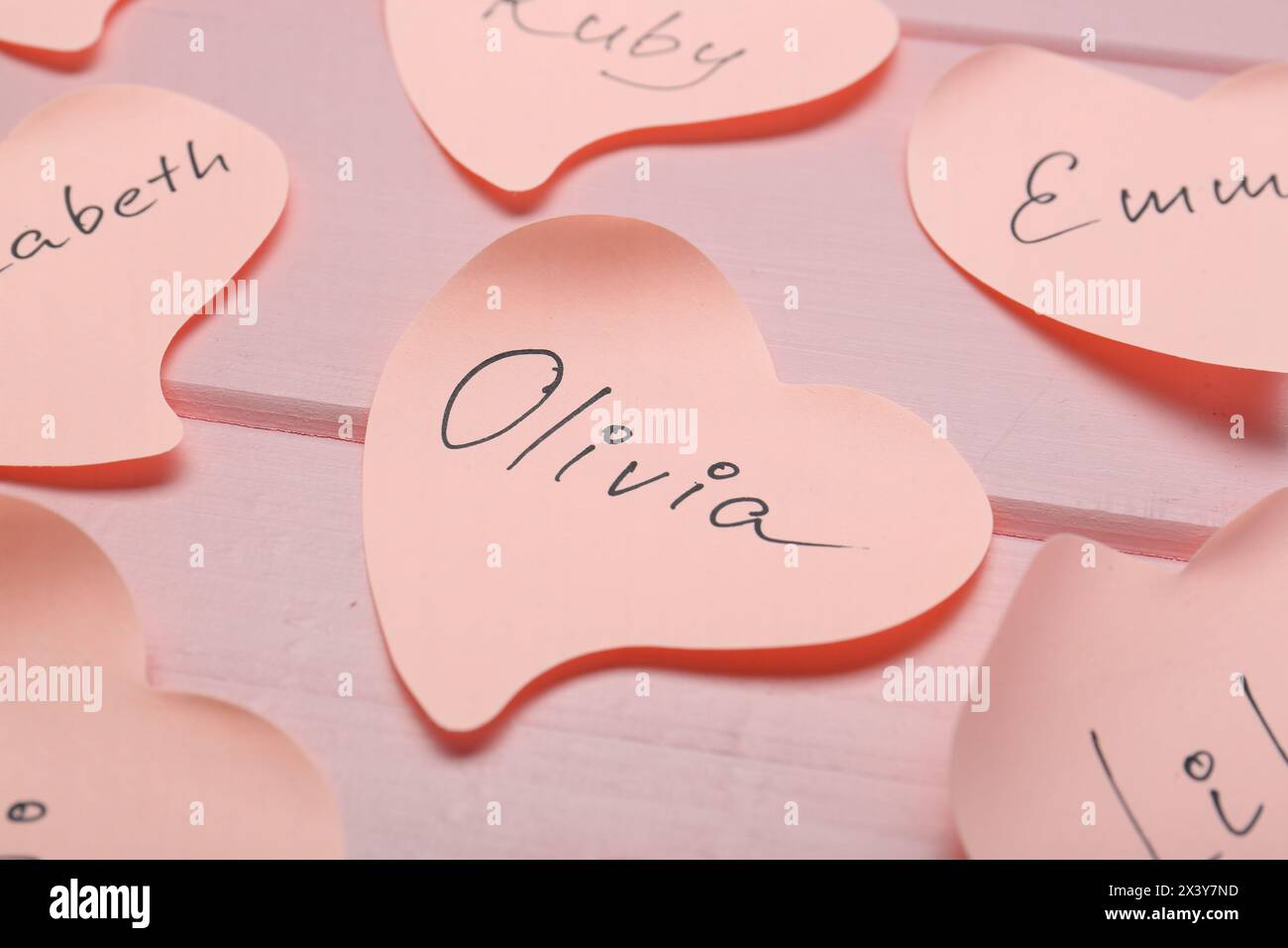 Paper stickers with different names on pink wooden table, closeup ...