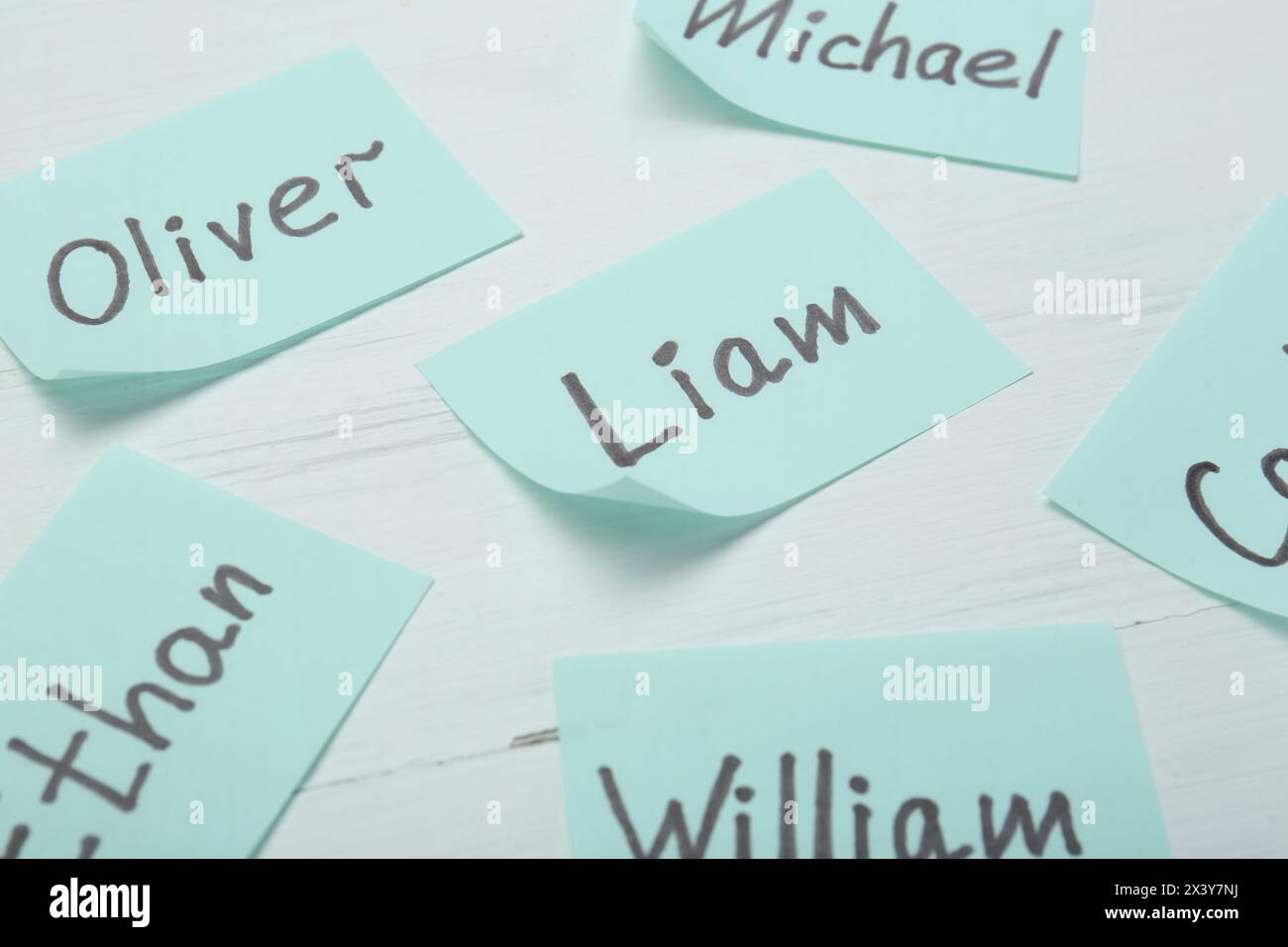 Paper stickers with different names on white wooden table, closeup ...