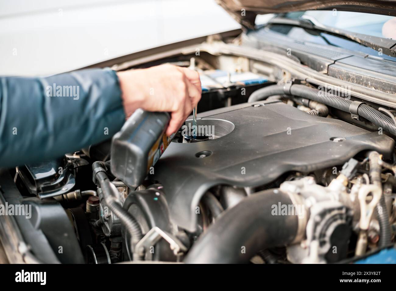 A man pours motor oil into a car engine. Changing and adding oil, car ...