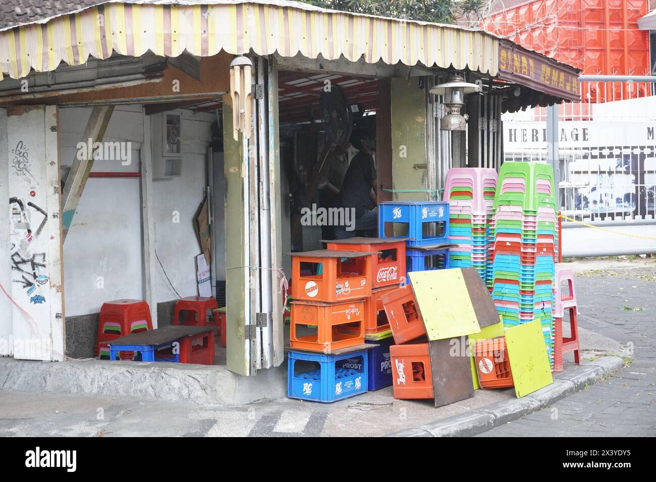 Stacks of empty drink bottle crates and piles of short plastic chairs ...