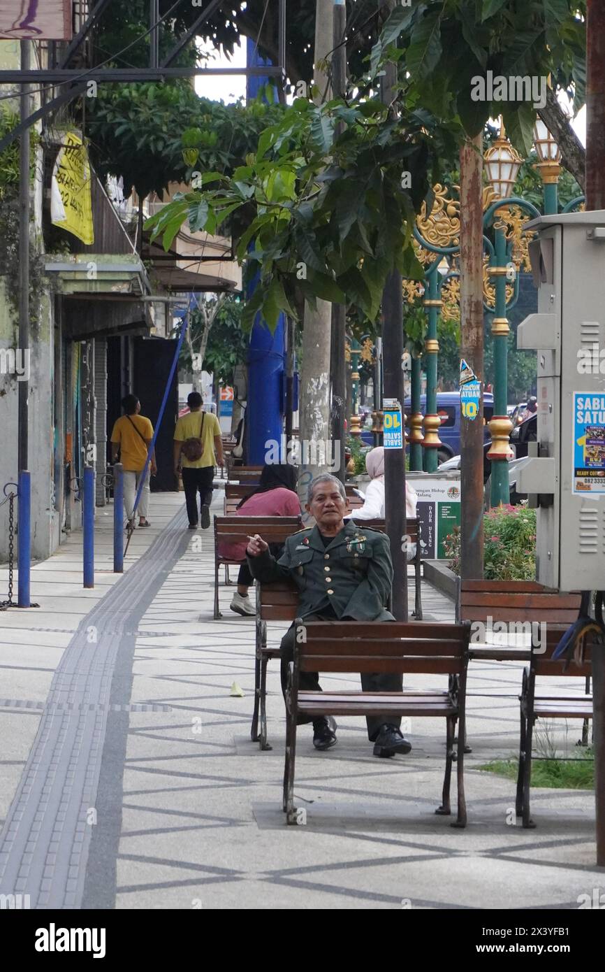 An old man in old army uniform sat on the sidewalk alone Stock Photo ...