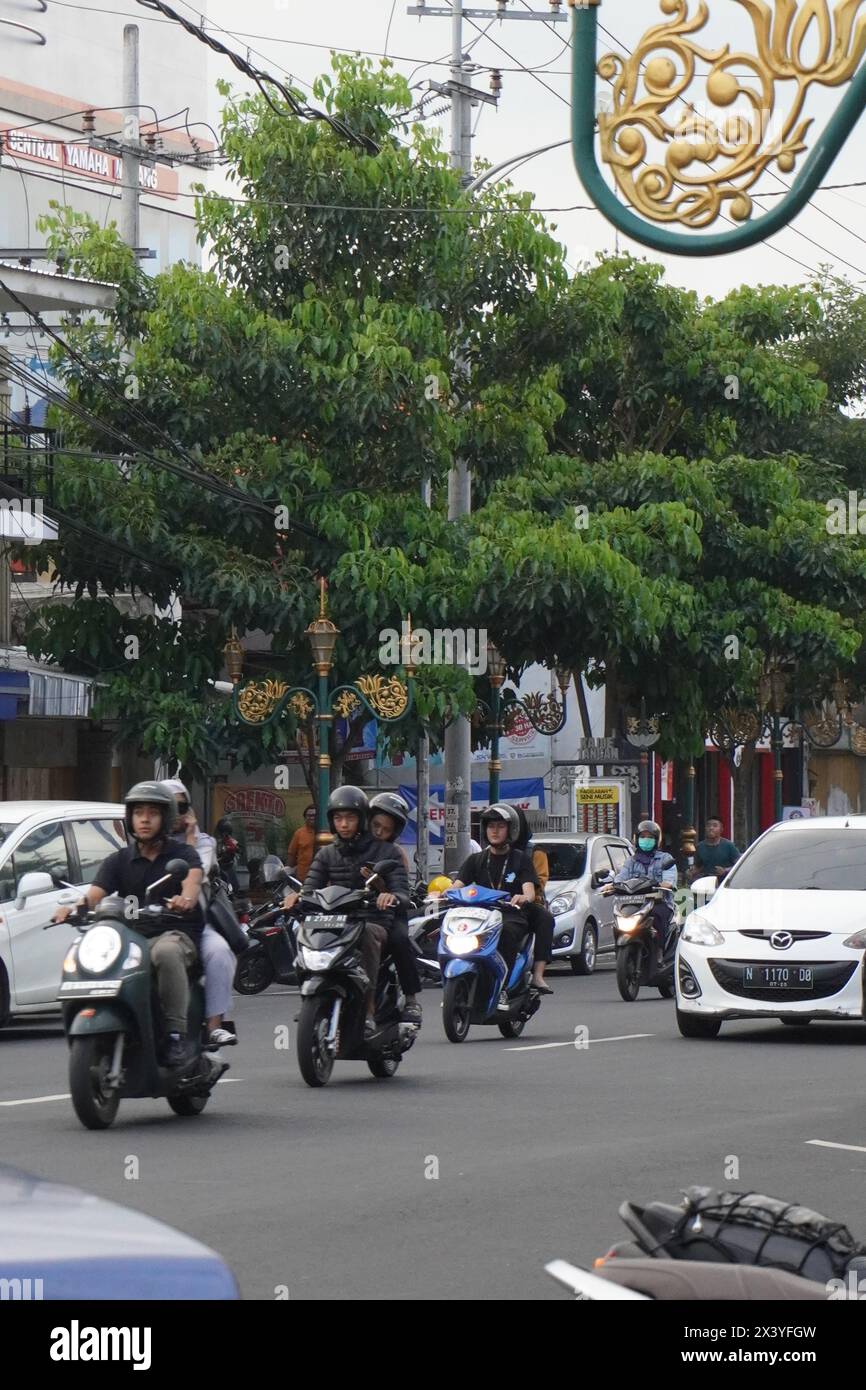 The highway in the city of Malang is busy with motorbikes and cars in ...