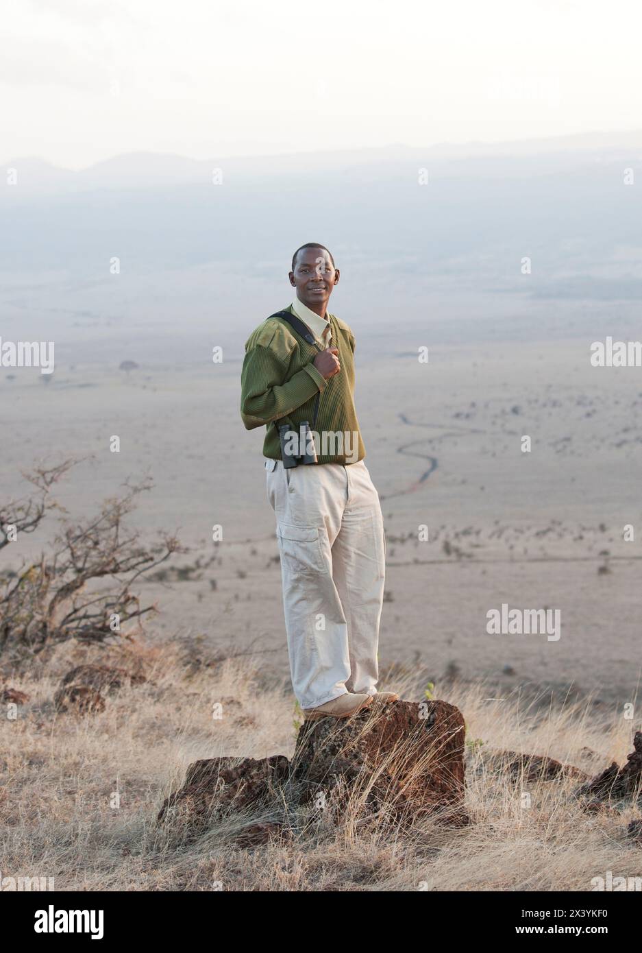 A Kenyan guide poses for a portrait on top of a rock during a game ...