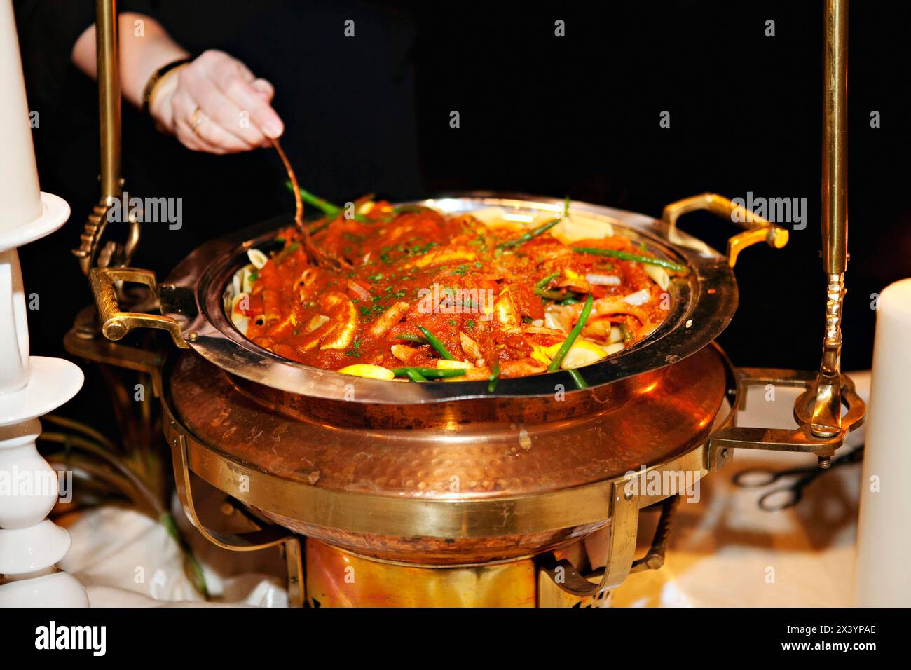 Chef serves gourmet pasta from a steaming chafing dish Stock Photo - Alamy