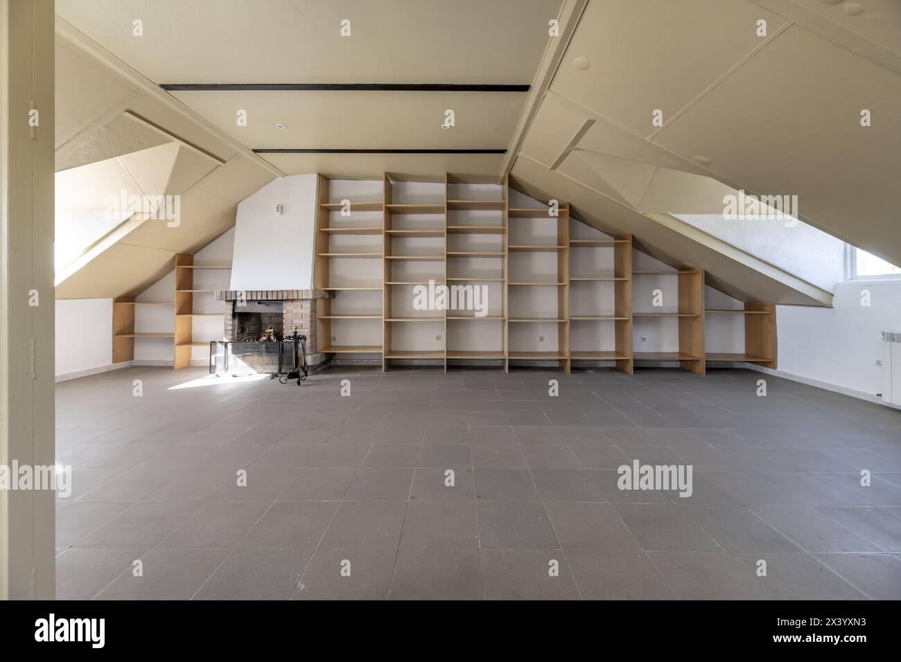 Large attic with a wall of shelves, windows with skylights, a fireplace ...