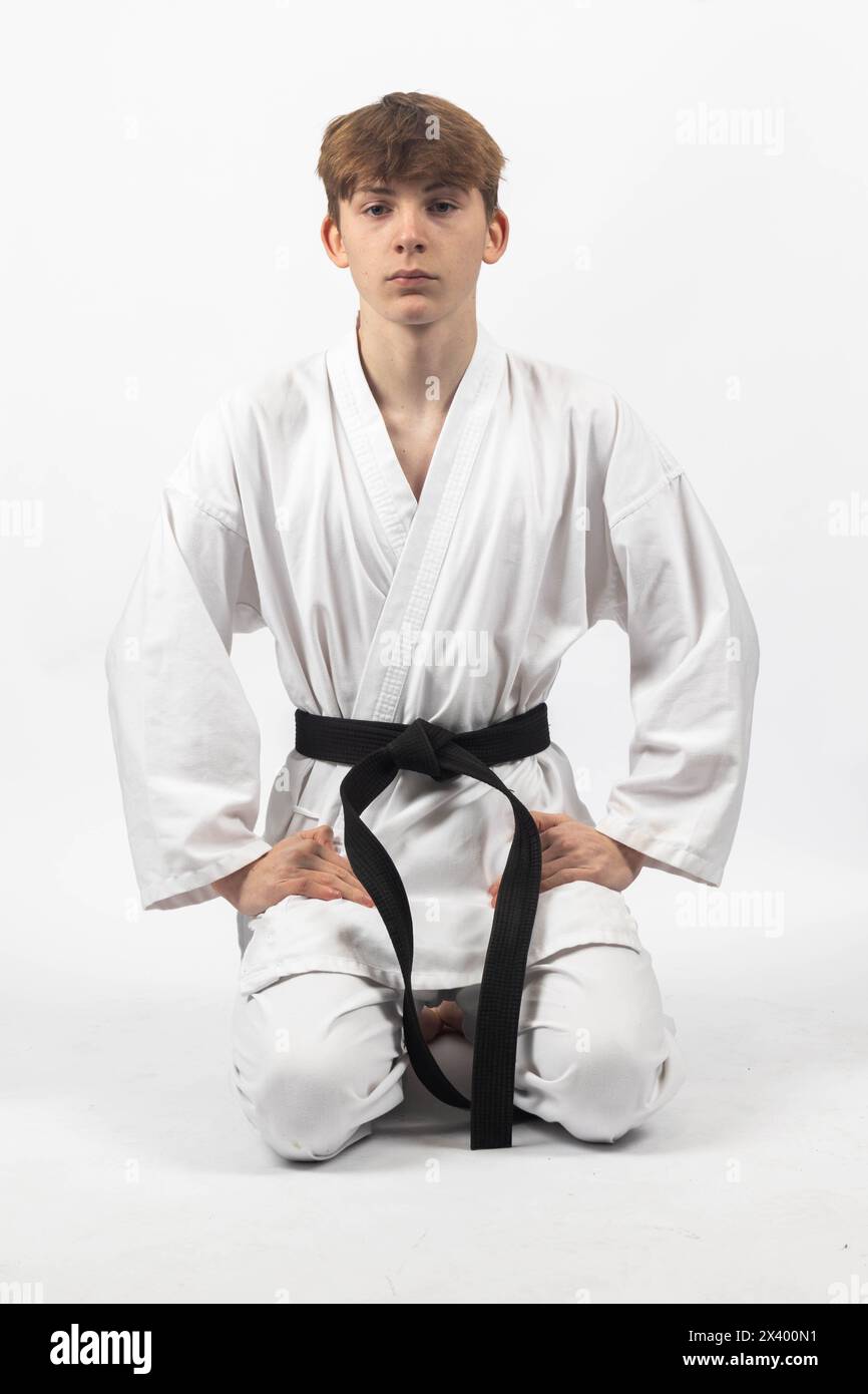 A 15 year old Karate Blackbelt boy, wearing A Gi performing kneeling in ...