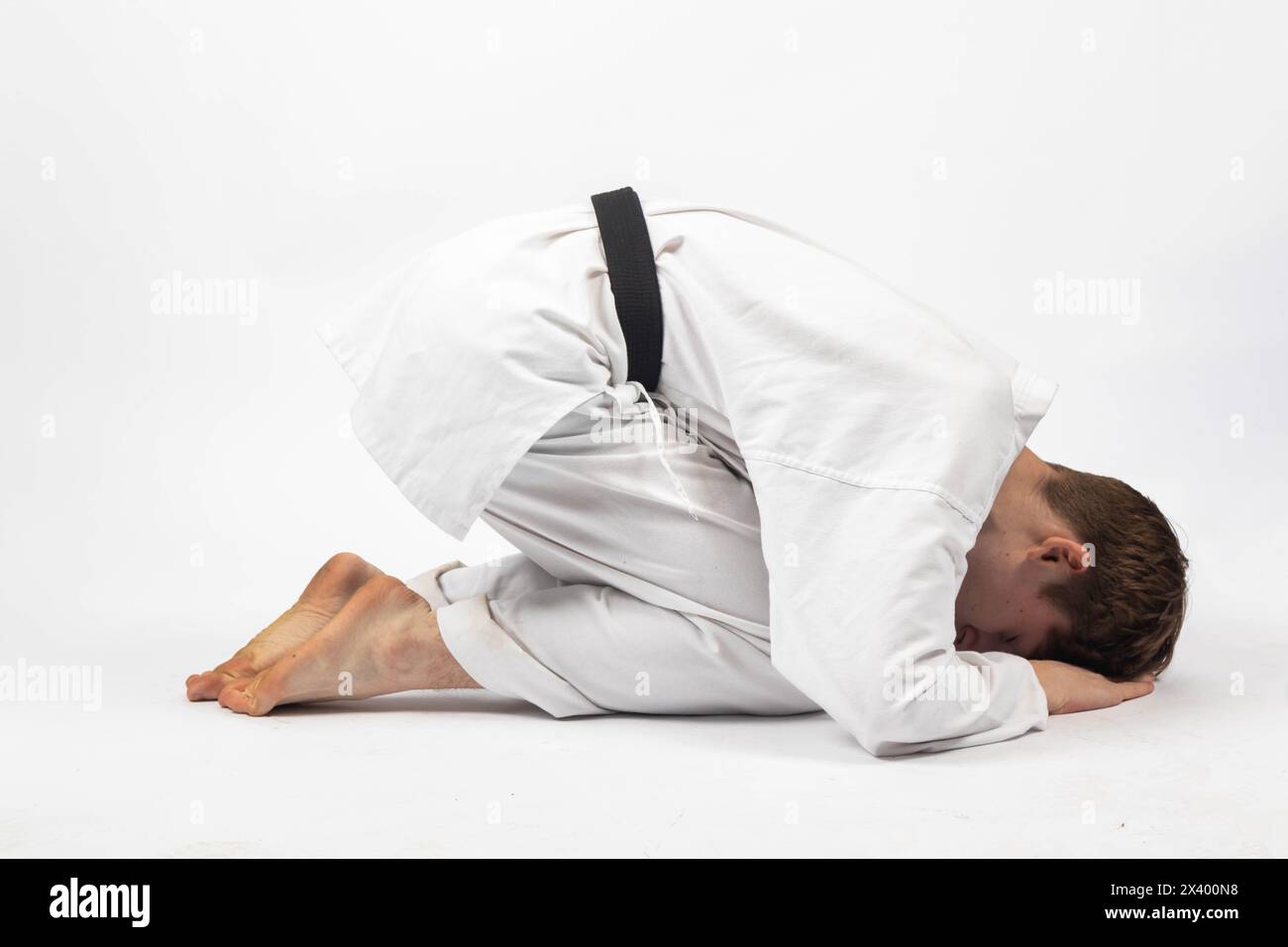 A 15 year old Karate Blackbelt boy, wearing A Gi performing a bow from ...