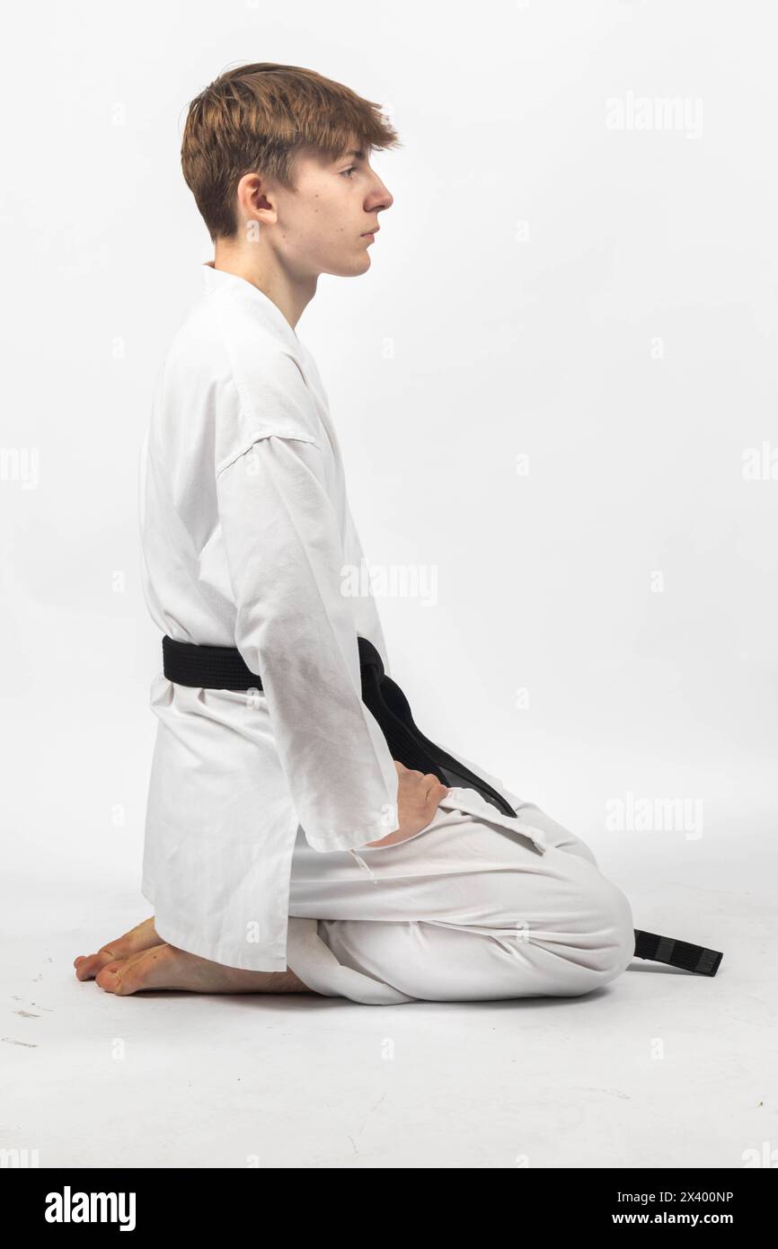 A 15 year old Karate Blackbelt boy, wearing A Gi performing kneeling in ...