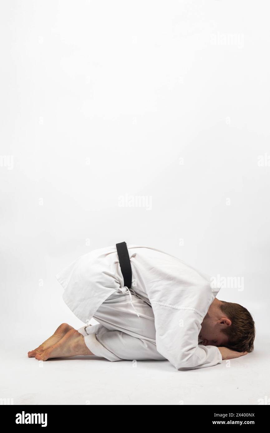 A 15 year old Karate Blackbelt boy, wearing A Gi performing a bow from ...
