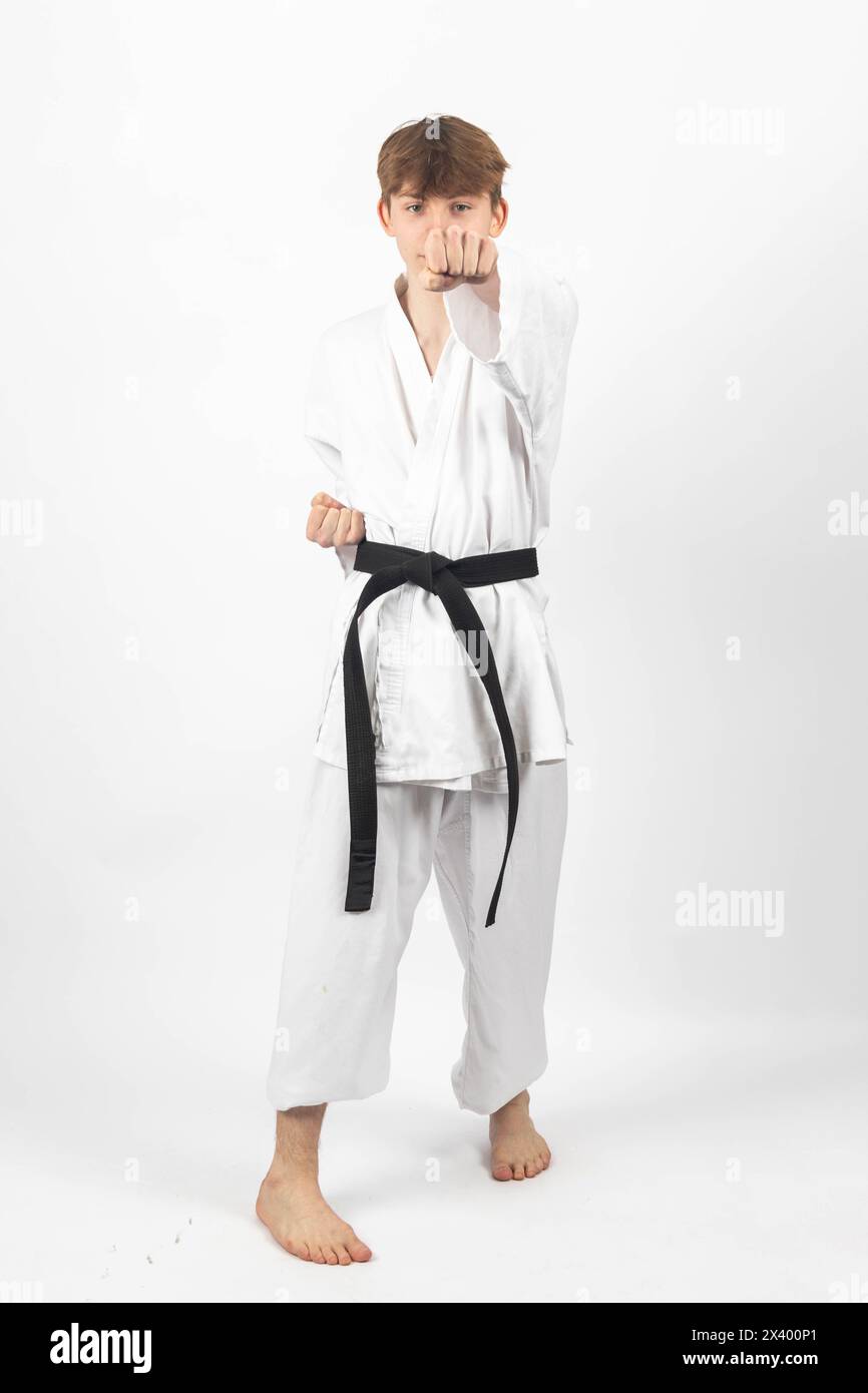A 15 year old Karate Blackbelt boy, wearing A Gi performing a punch ...