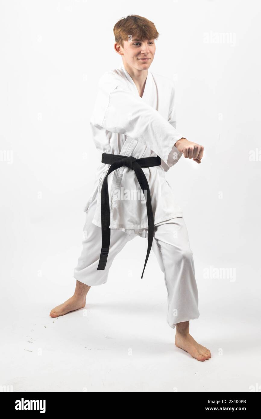 A 15 year old Karate Blackbelt boy, wearing A Gi performing a punch ...