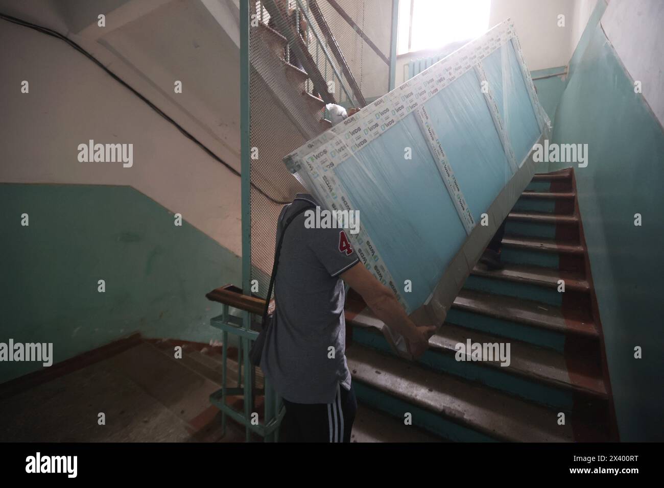KHARKIV, UKRAINE - APRIL 27, 2024 - Men carry a glass unit up the ...