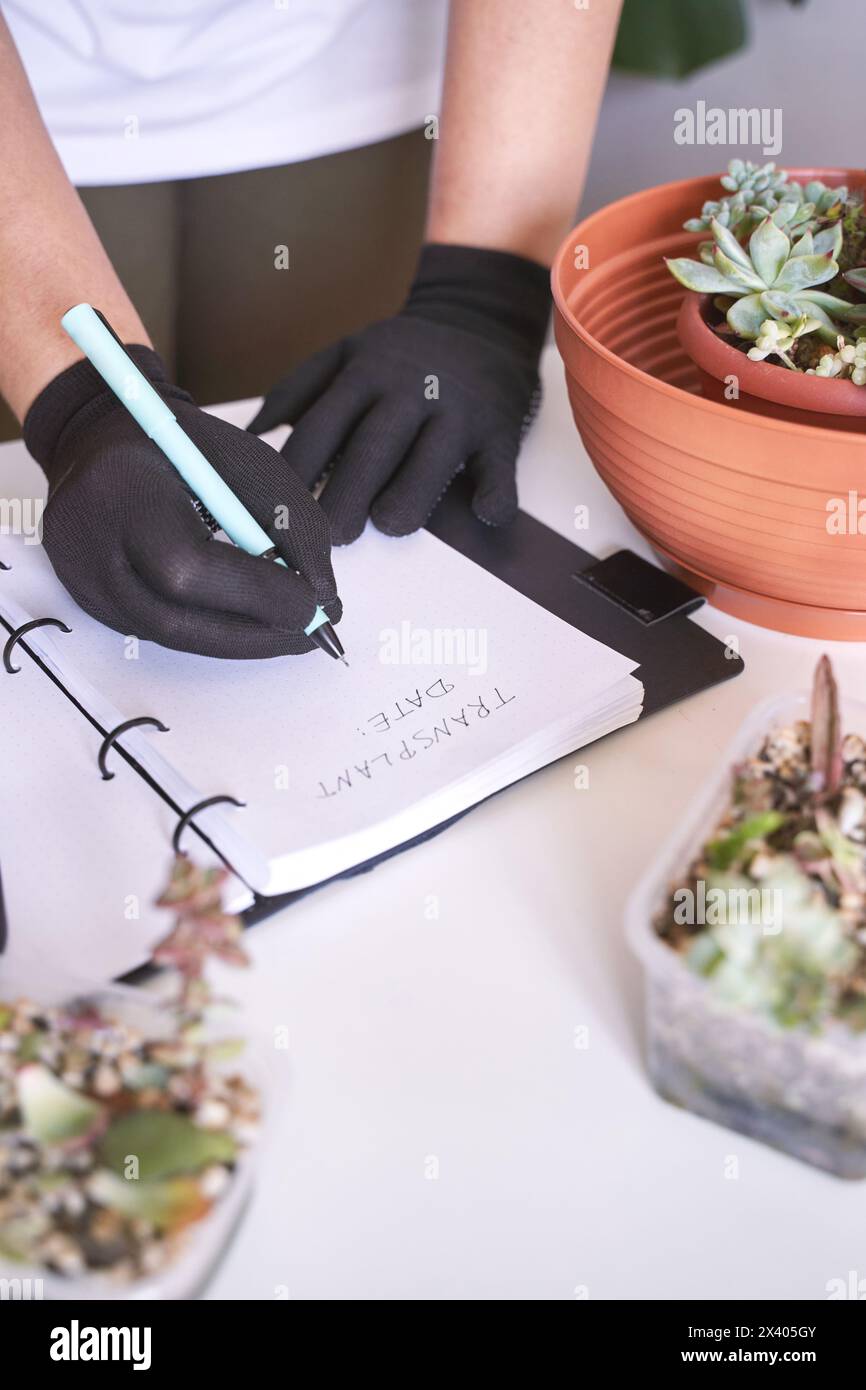 A woman, engaged in gardening, writes notes in notebook. Surrounded by ...