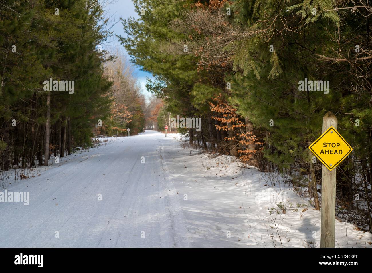 Stop ahead sign on a snow covered snowmobile and hiking trail through a ...