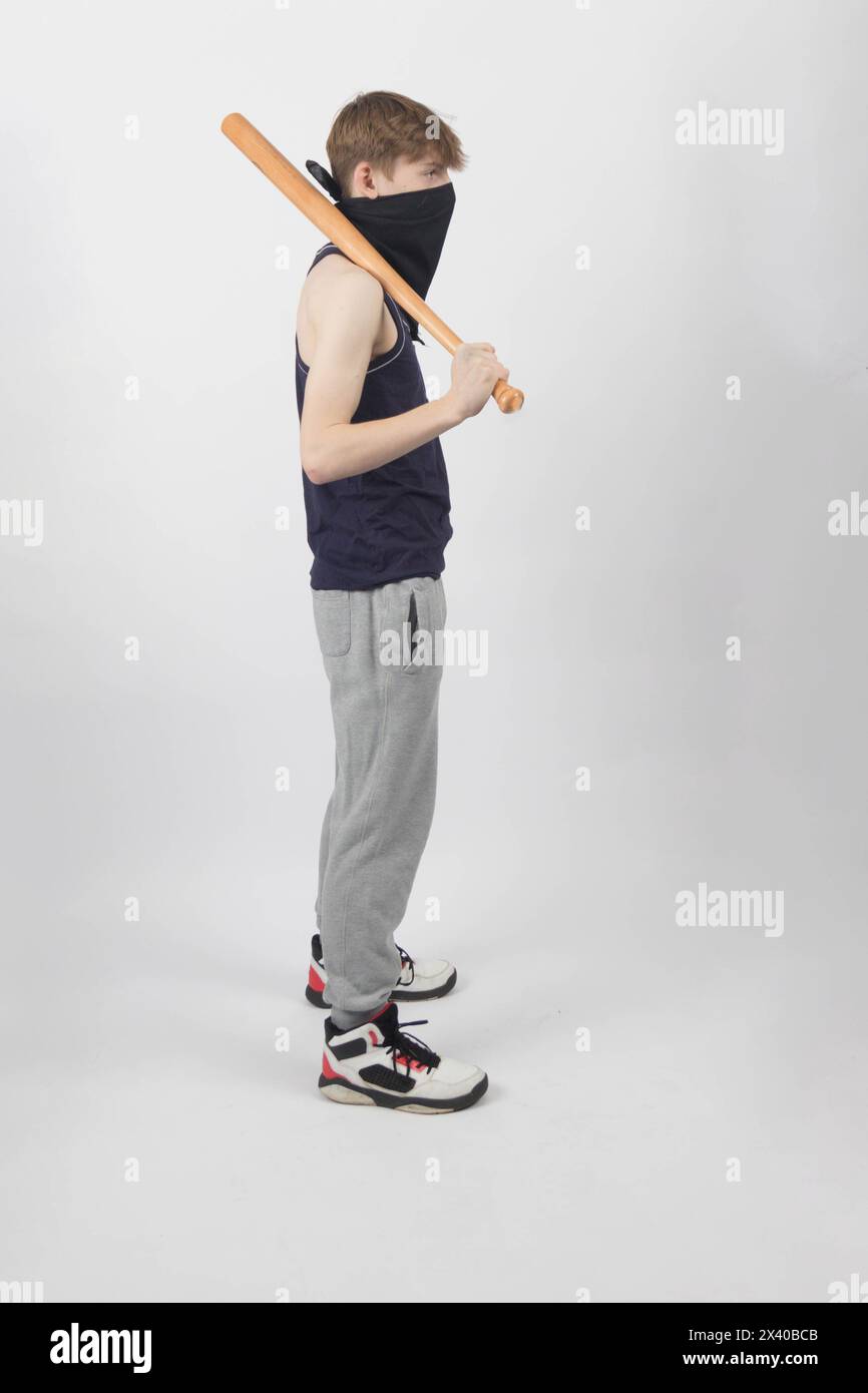 A Teenage Male Gang Member in a mask holding a baseball bat sideways ...