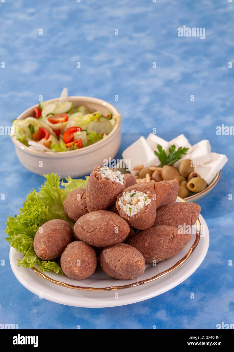 fried Arabic Lamb feta cheese Kibbeh with salad on blue background Stock Photo - Alamy