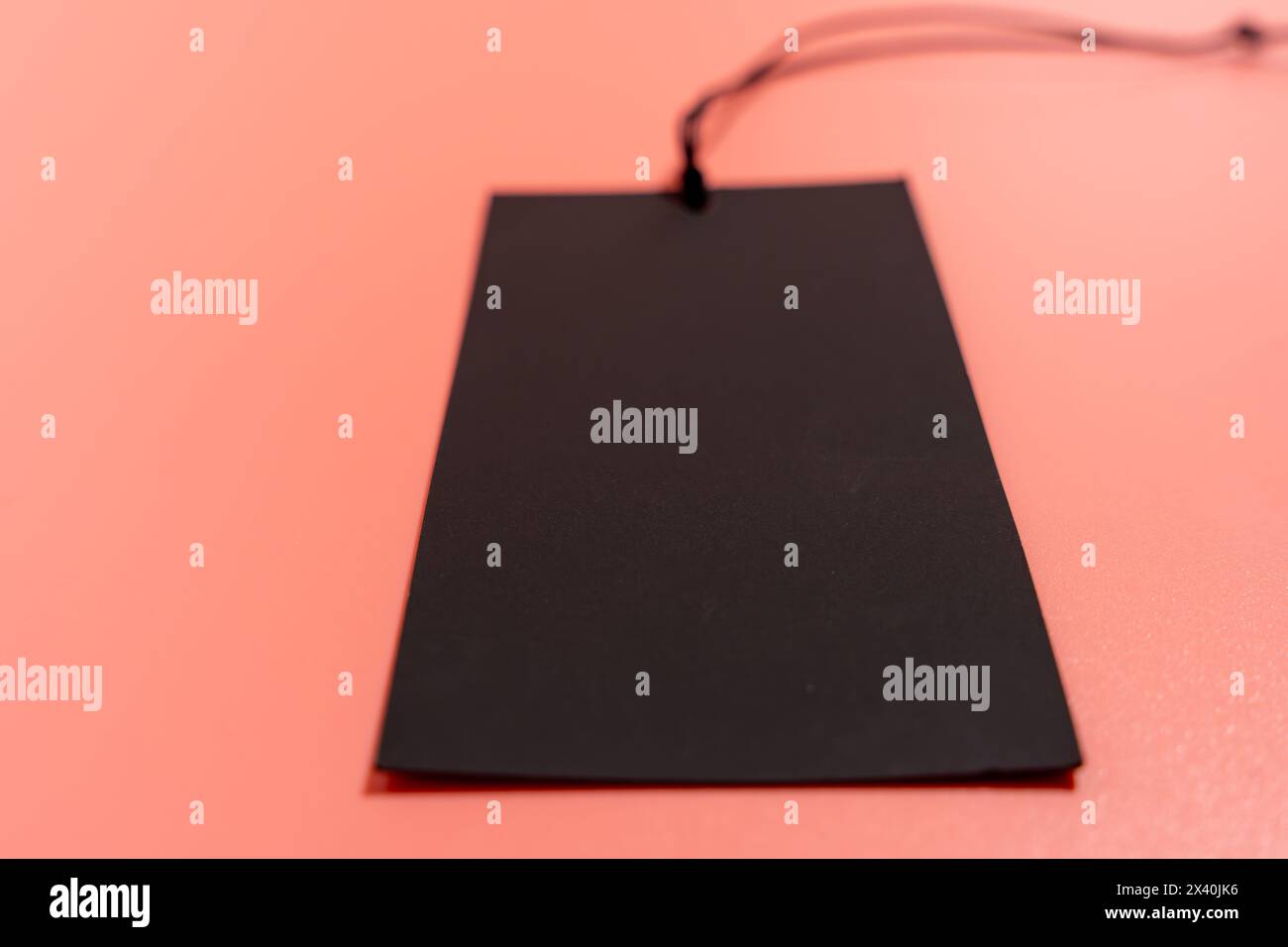 Black label with black cord with space for writing on a pink background ...