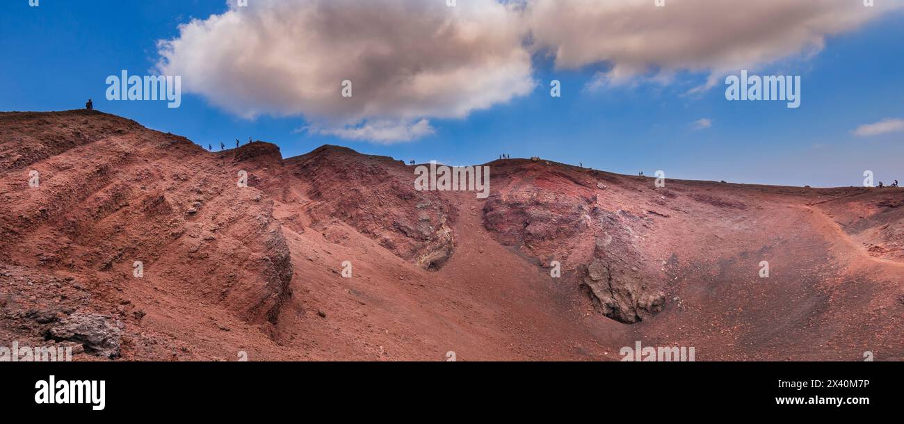 Tourists walk across the ridgeline on the rugged and harsh landscape of ...