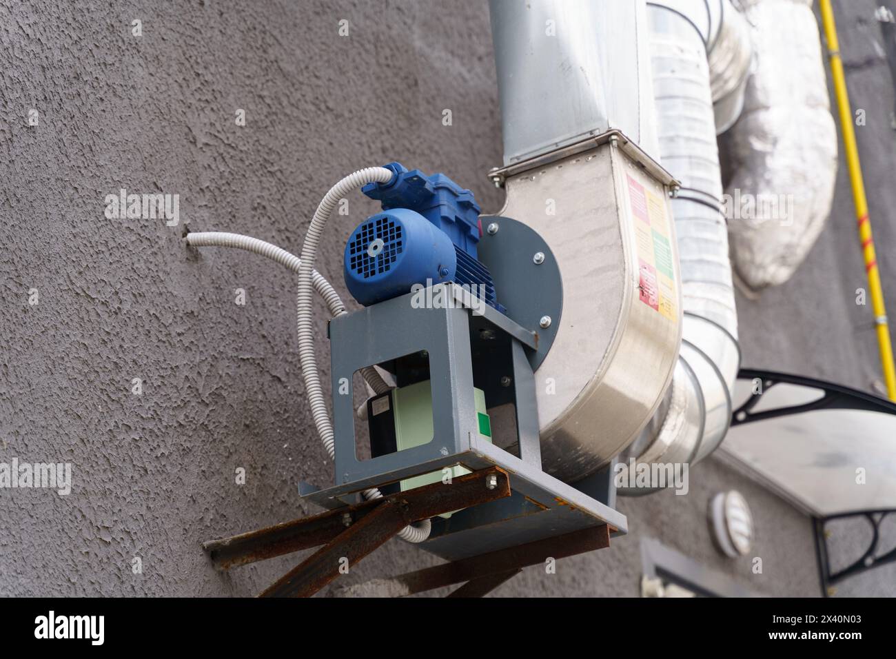 Close-up view of a wall-mounted exterior ventilation unit with conduit ...
