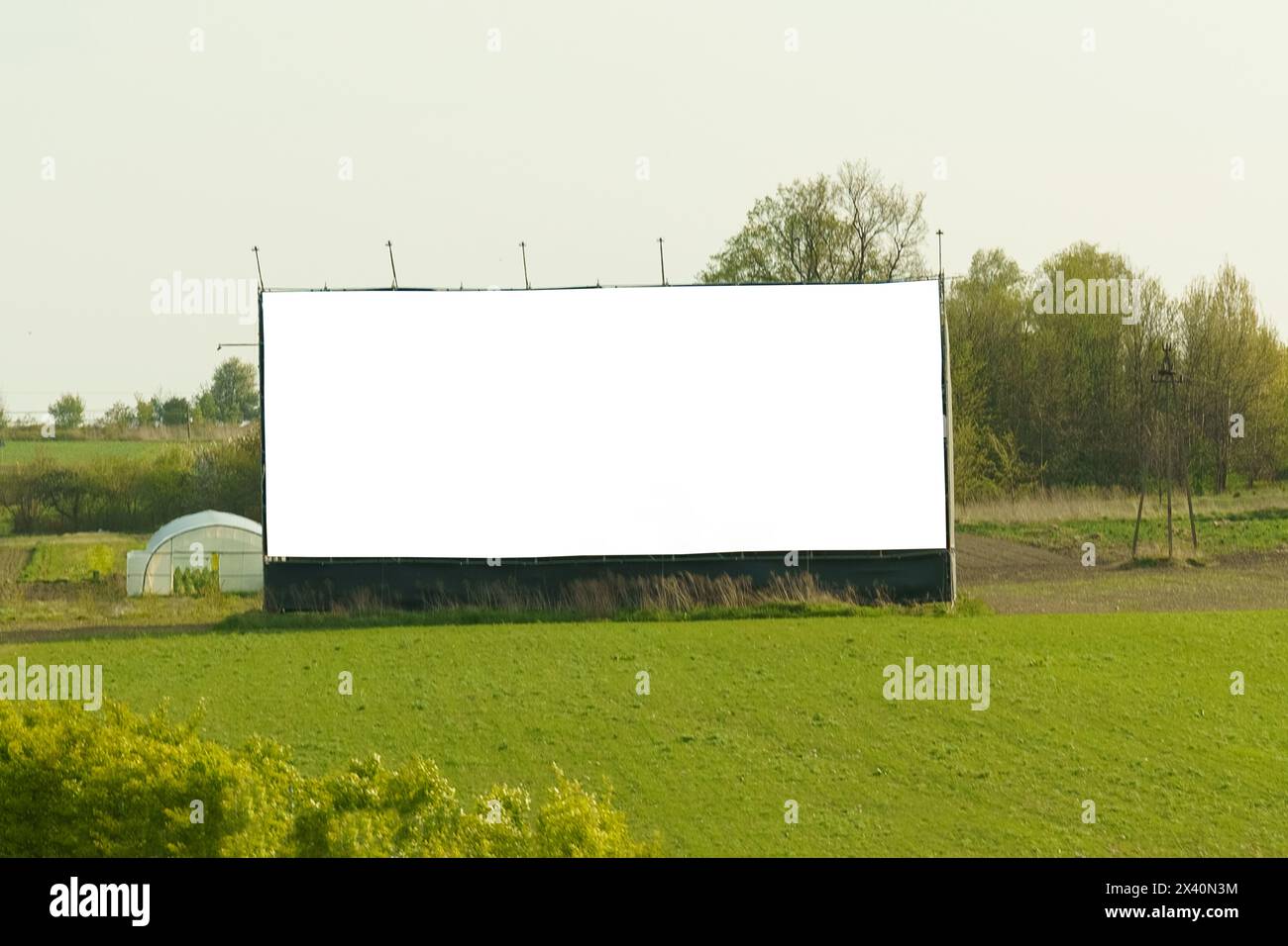 A big LED screen stands tall amidst a vast green field, creating a ...