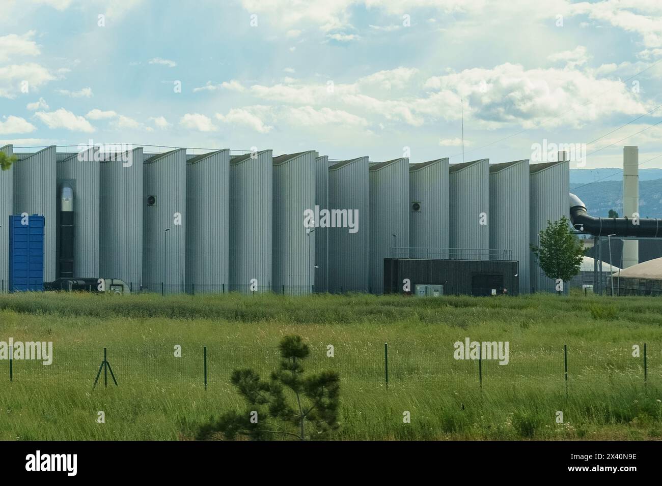 A substantial building stands prominently amidst a vibrant green field ...