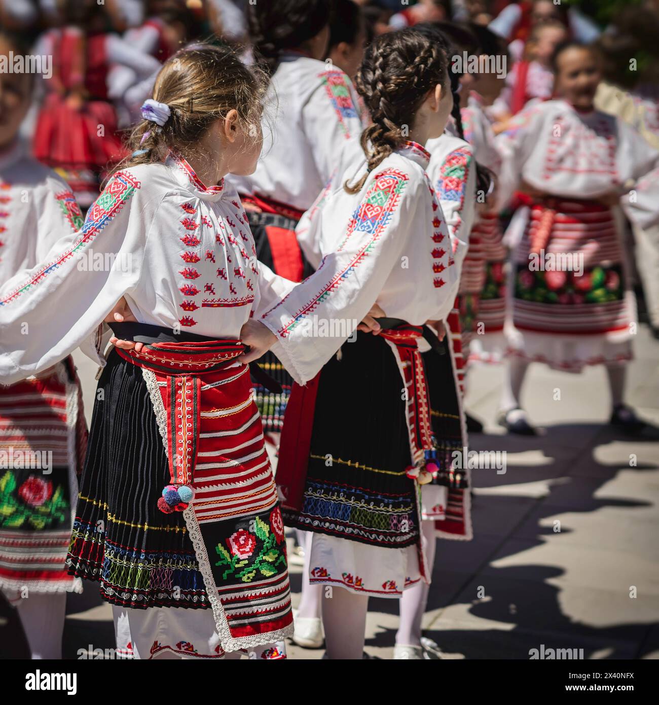 Girls in traditional costumes dance Bulgarian folk dances, summer sunny ...