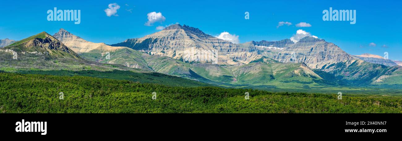 Panorama of a mountain range with green rolling foothills with blue sky ...