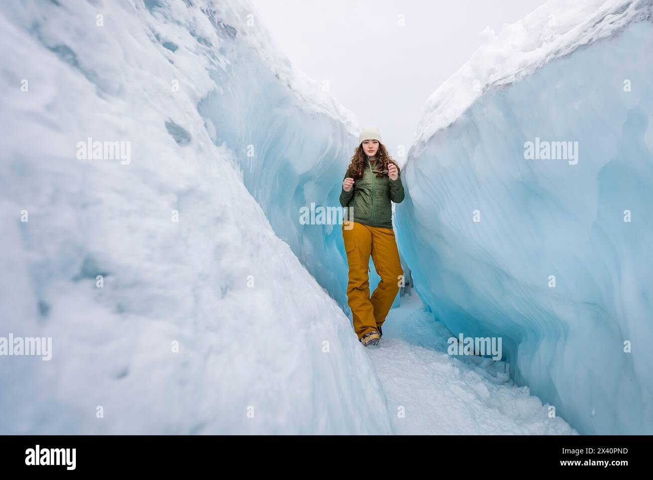 Teenage girl walking on the Matanuska Glacier in between blue ice walls ...