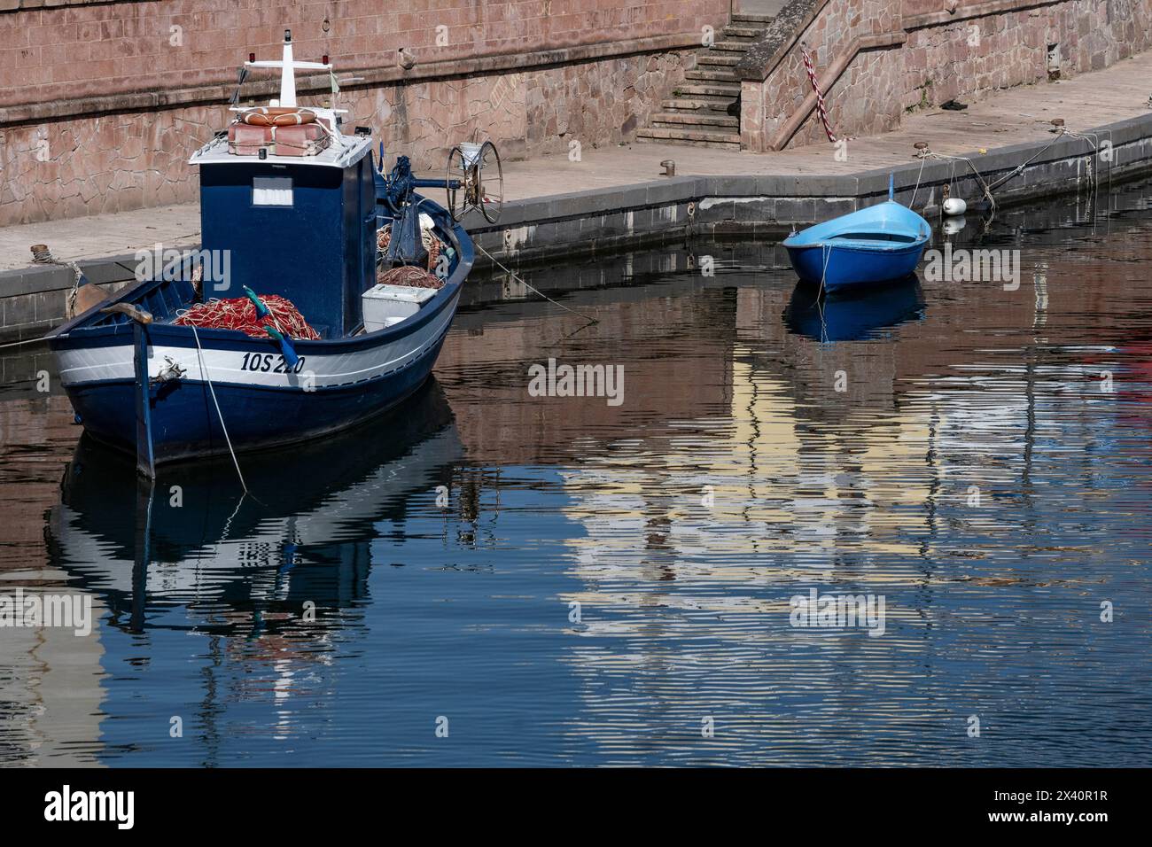 Fishing boat and rowboat moored in the tranquil water in a harbour in ...