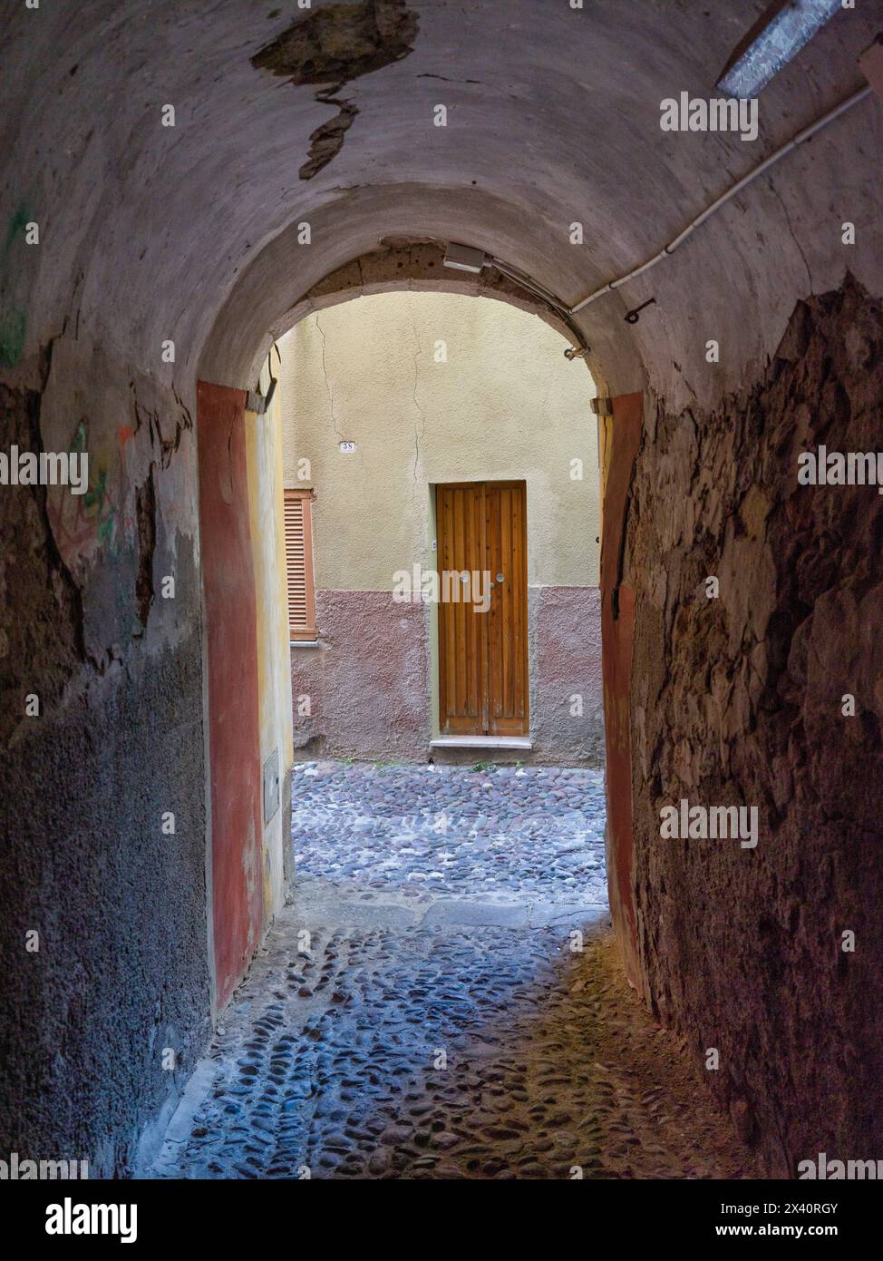 Arched covered narrow walkway with cobblestone; Bosa, Sardinia, Italy ...