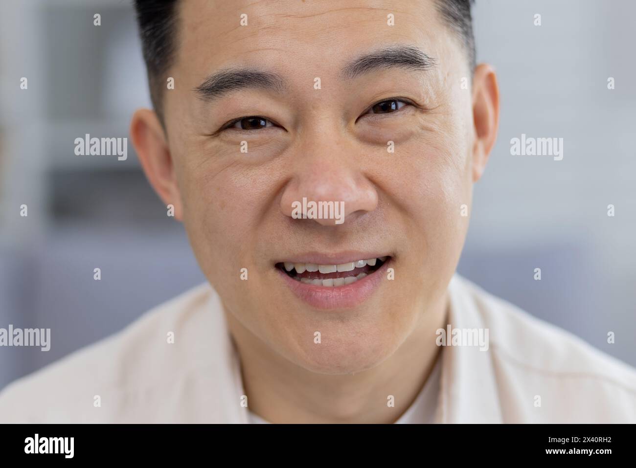 A high-resolution image featuring a close-up portrait of a cheerful middle-aged Asian man. His ...